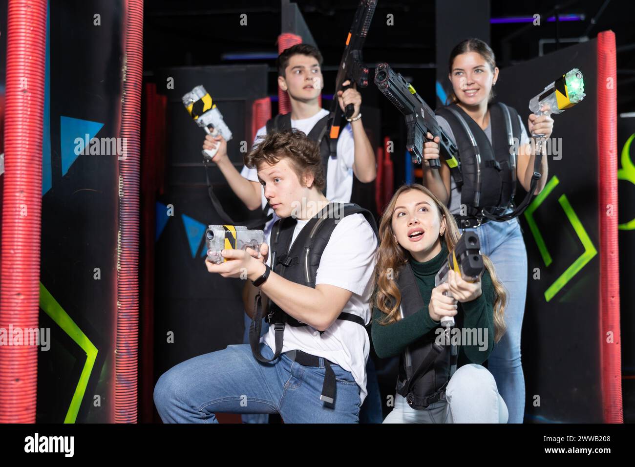 Four people with lasertag guns squatting in arena Stock Photo - Alamy