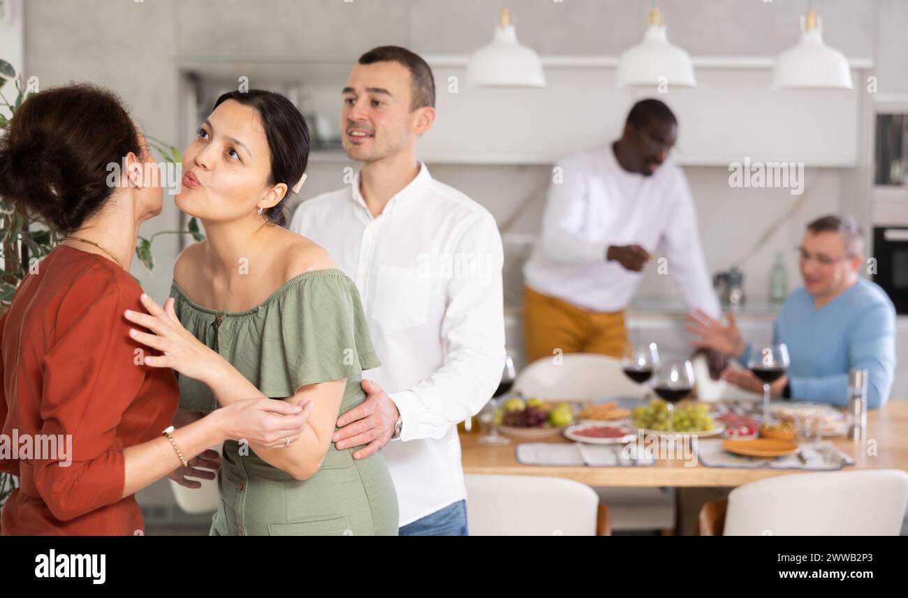 Women greet each other with kiss on cheek before festive dinner. Men ...