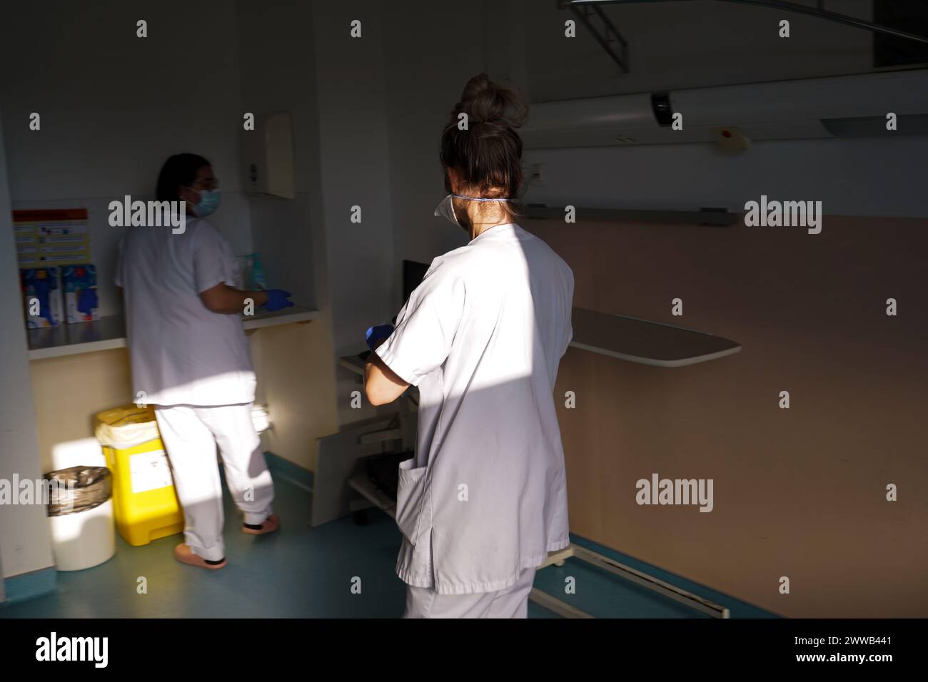 Two nursing assistants clean a room in the emergency room of a ...