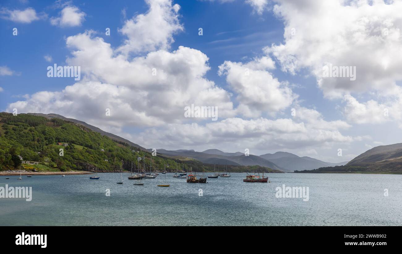 Fishing boats anchors in the gentle waters of Ullapool, set against the ...