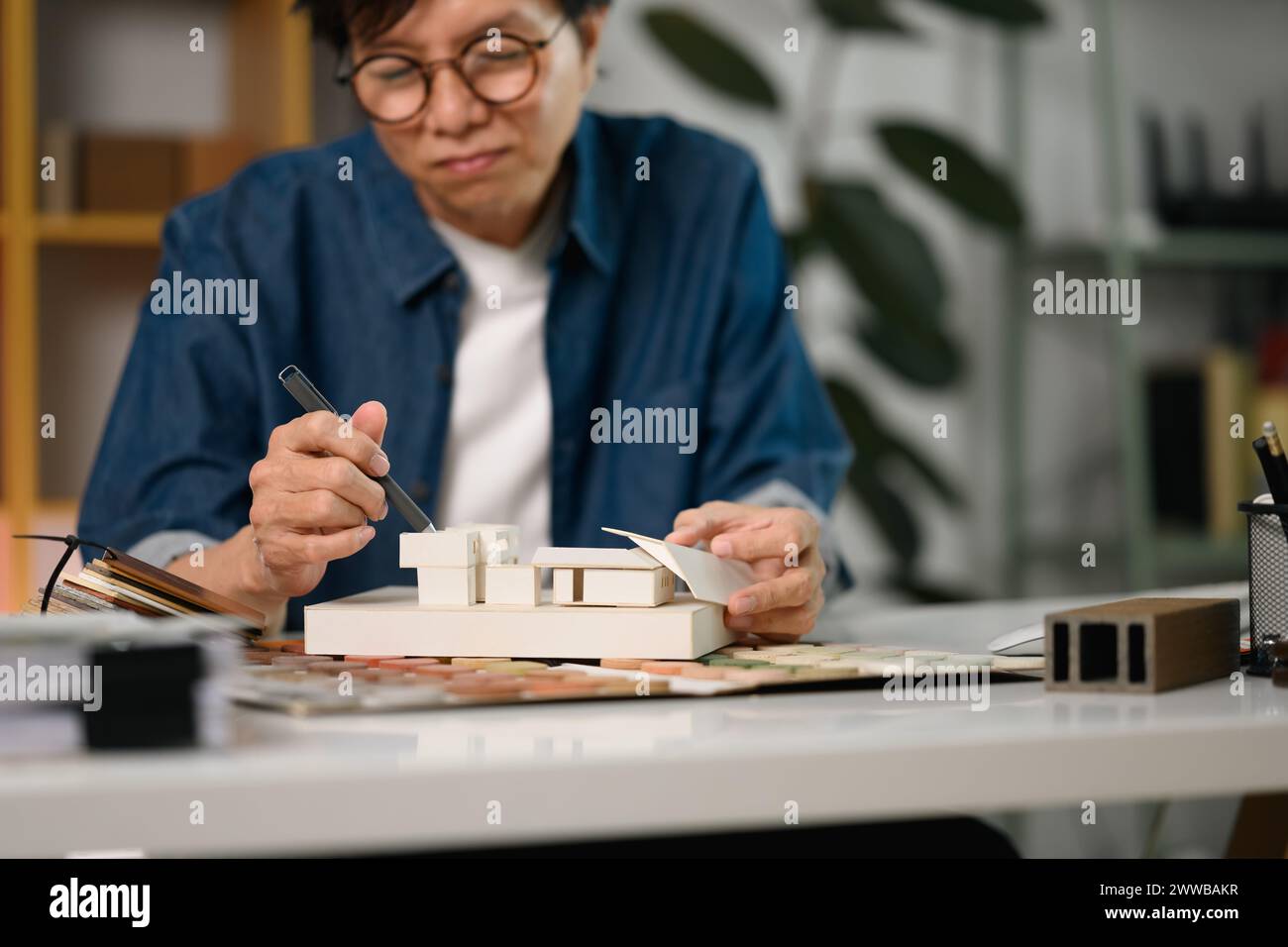 Portrait of senior male architect examining scale house model in his ...