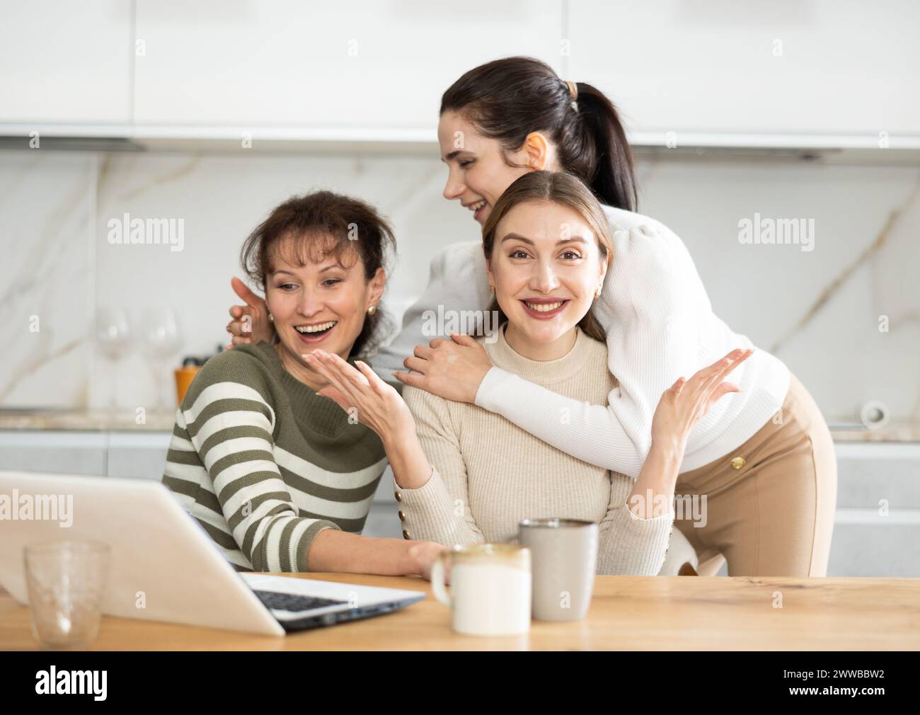 Three happy middle-aged woman expressing joy for winning in the kitchen ...