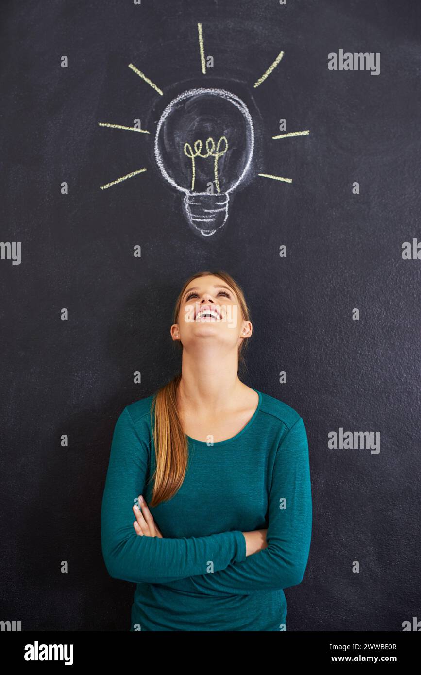 Idea, thinking and happy woman with light bulb on chalkboard for ...