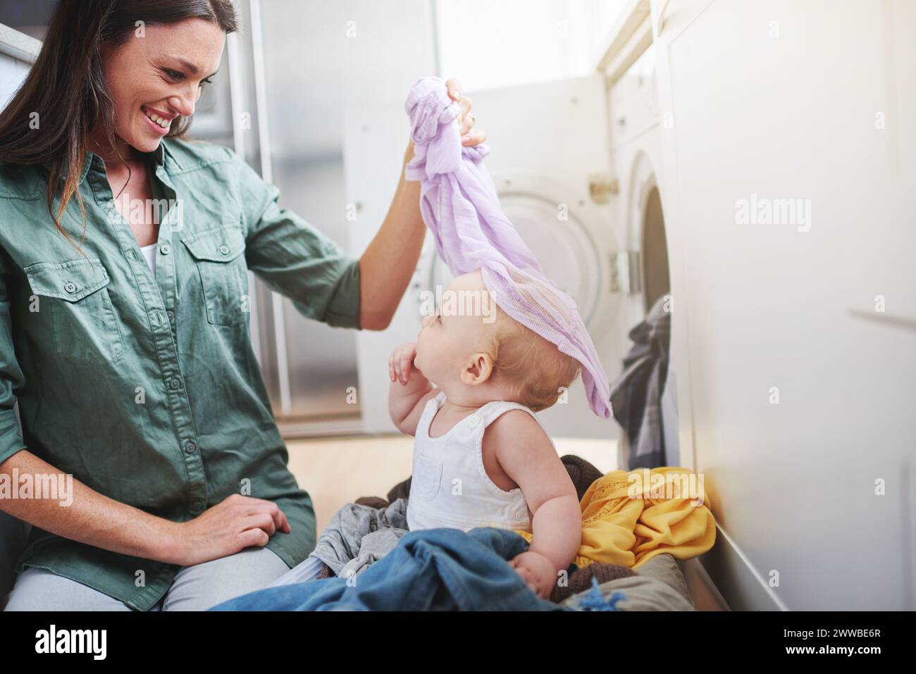 Laundry, washing and mother with baby in clothes for multitasking ...