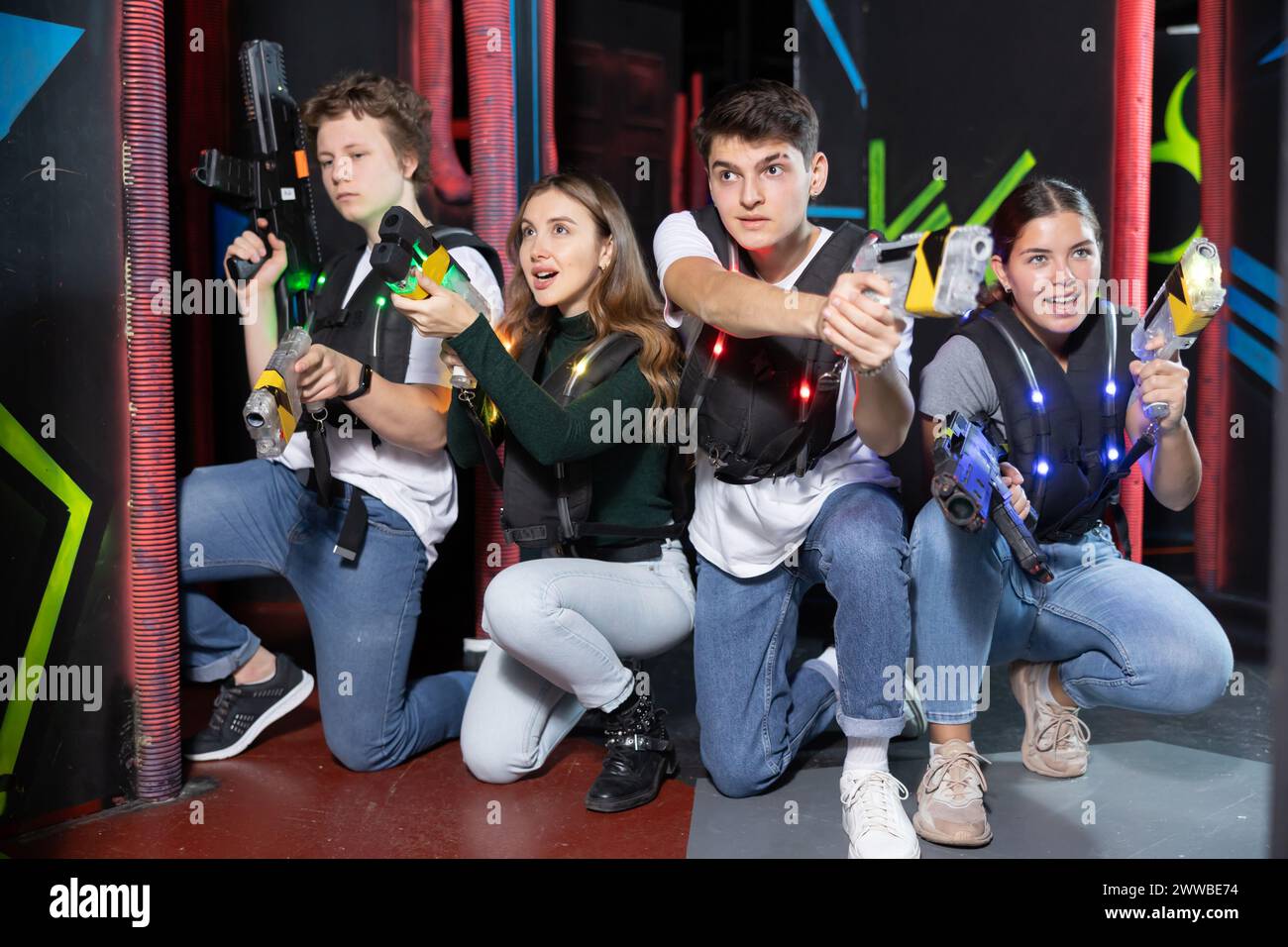 Laser tag players young mens and womens playing in teams in dark laser ...