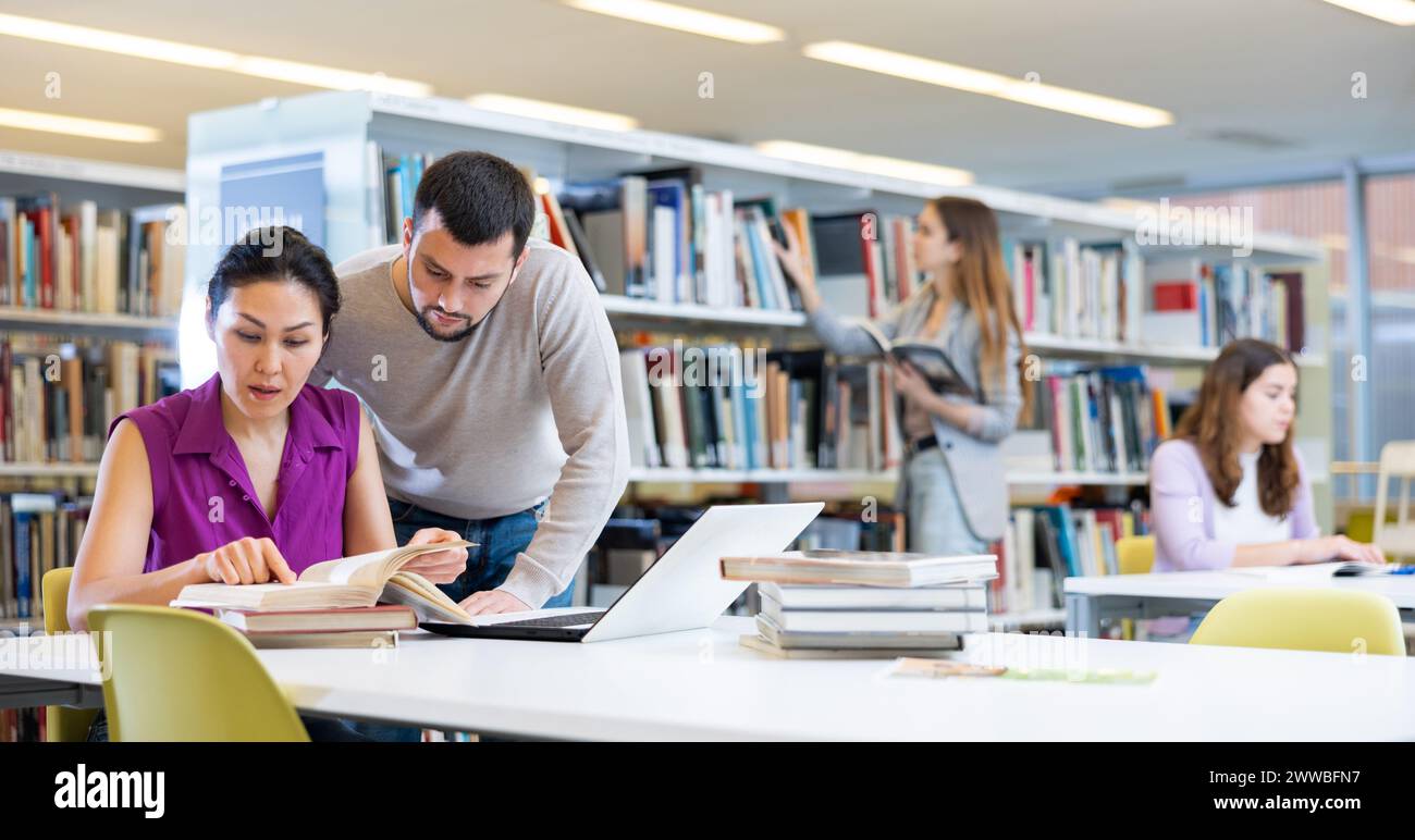 Man helping woman to prepare for exams in library Stock Photo - Alamy