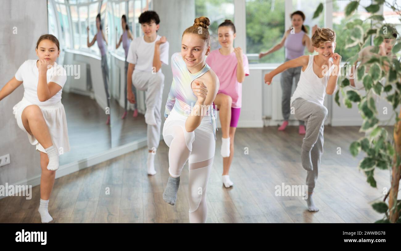 Woman teacher in background dances with students, inspects and observes skill of dancers Stock ...