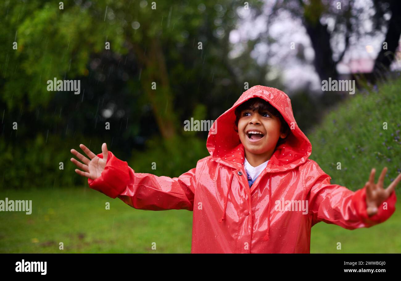 Rain, celebration and excited boy in a forest for adventure, freedom or ...
