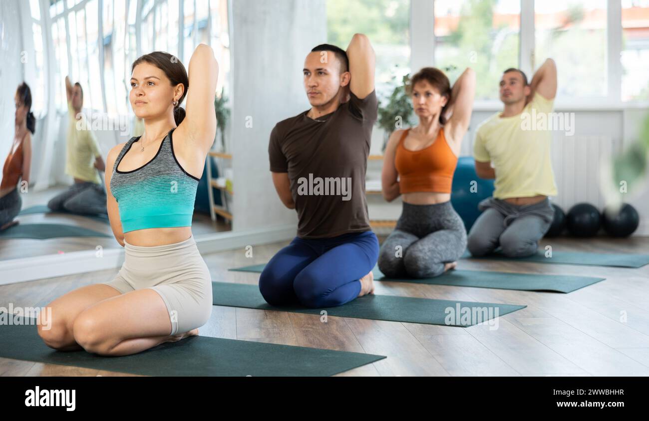 Group of sporty people exercising yoga class making Gomukhasana Cow ...