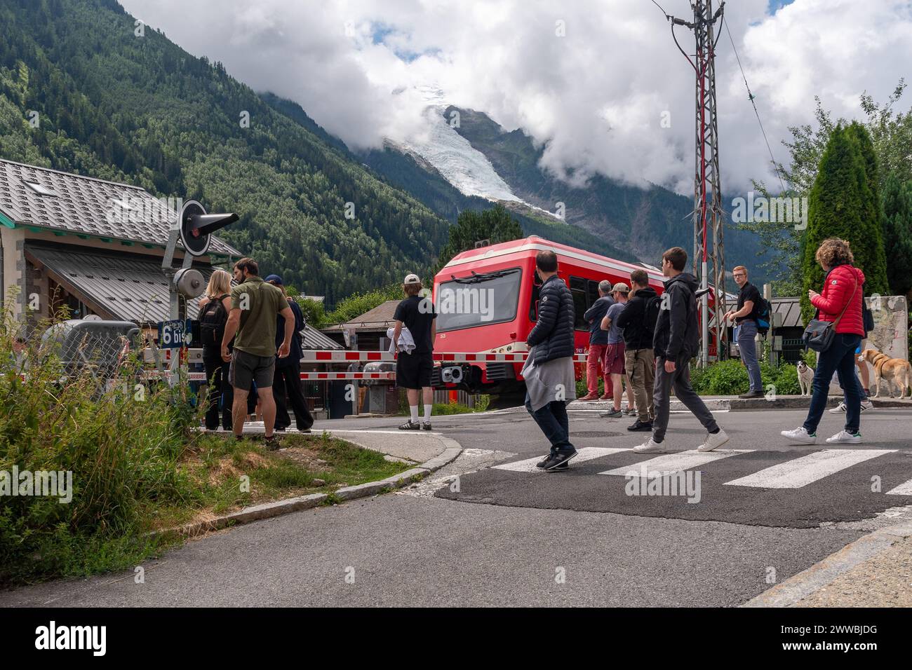People waiting for the passage of the train at the level crossing in the alpine town with Mont ...