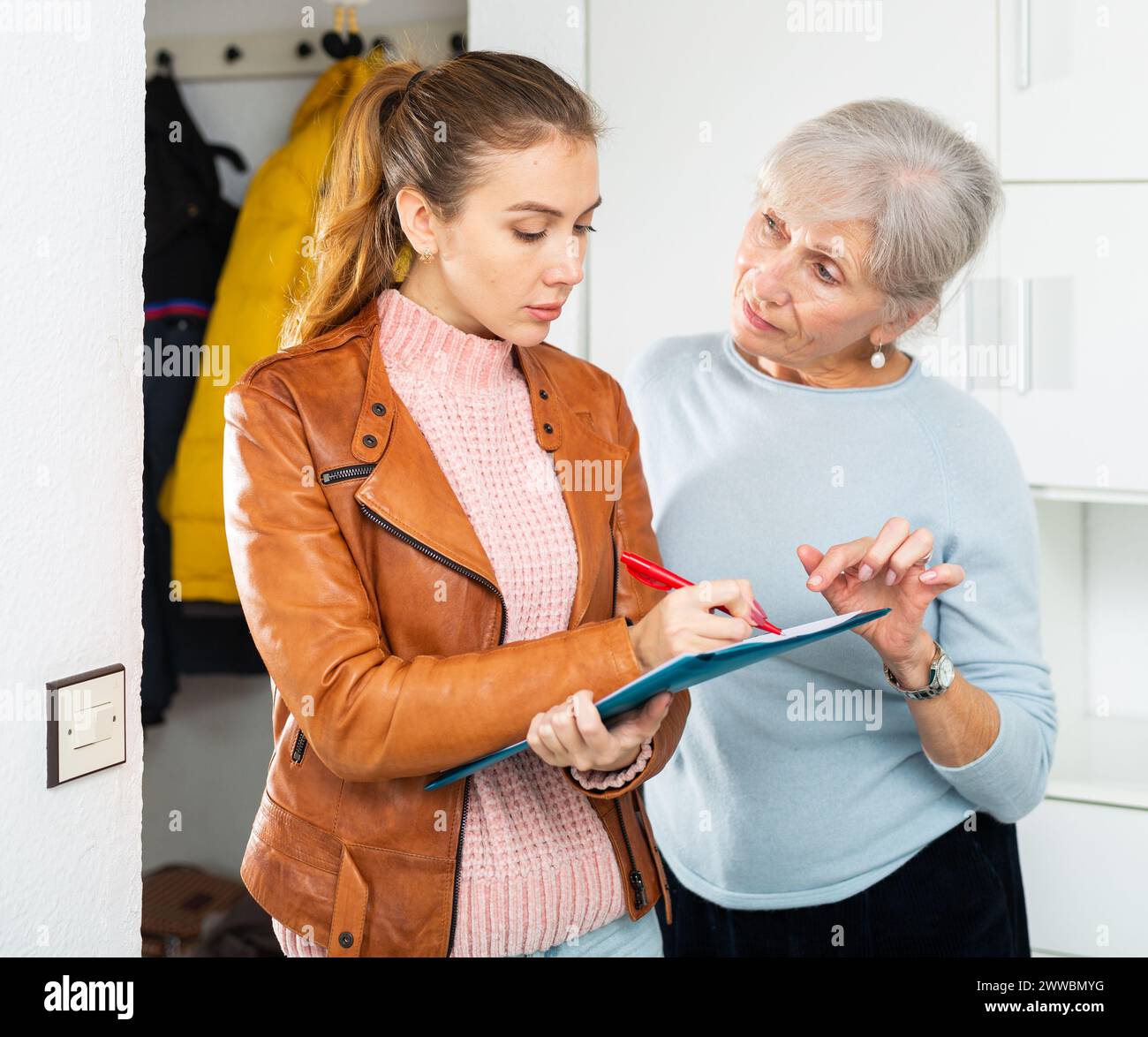 Senior and younger women filling rent contract Stock Photo - Alamy