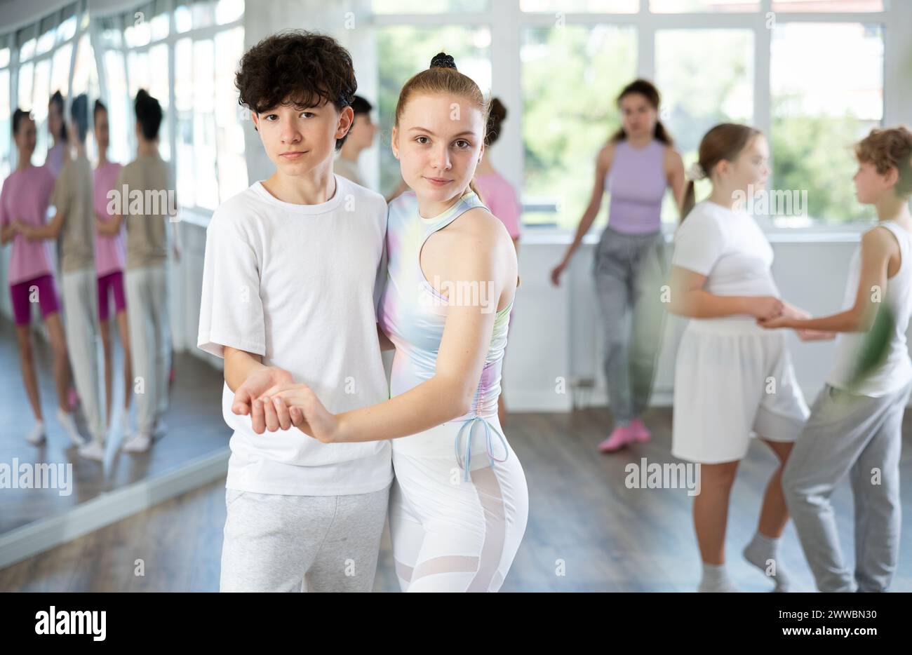 Group of positive teenagers learning to dance tango in dance studio ...