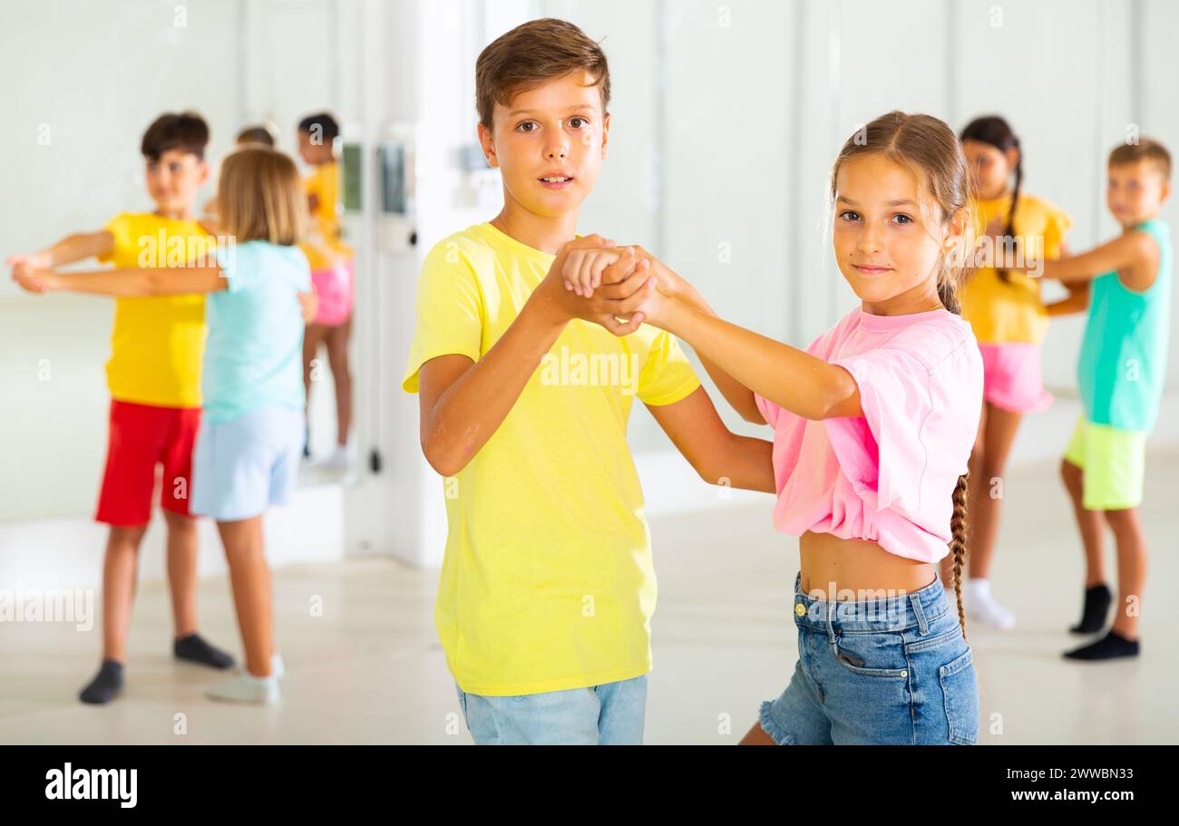 Tween boy and girl practicing slow pair dancing during group class ...