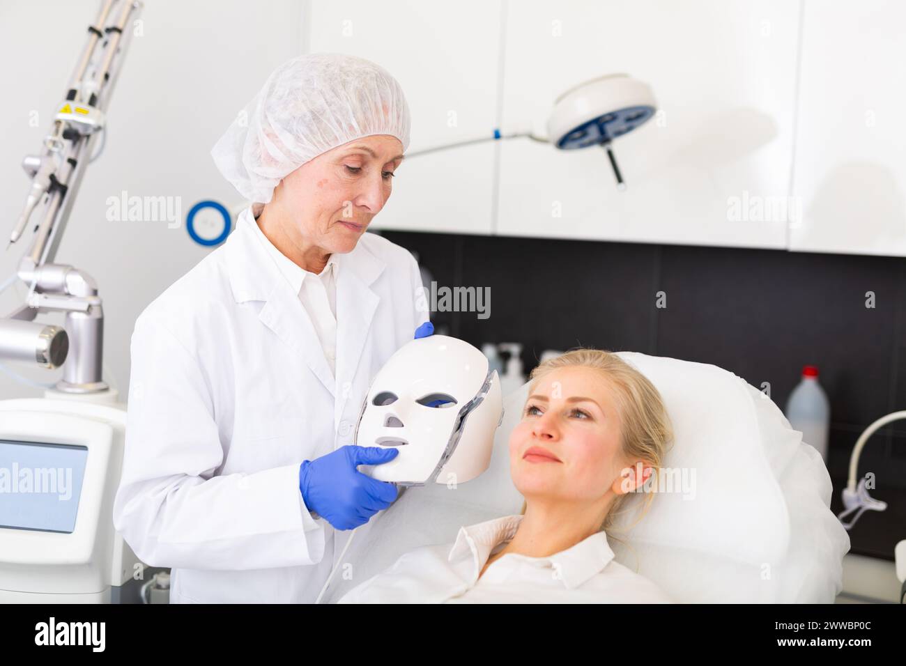 Young woman receiving facial light therapy in aesthetic medicine office ...