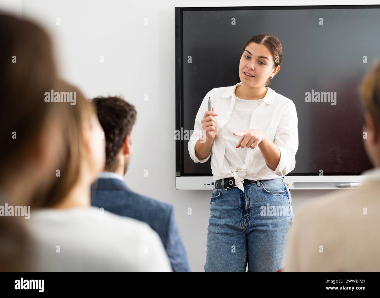 Positive skilled female coach explaining topic to group of people ...