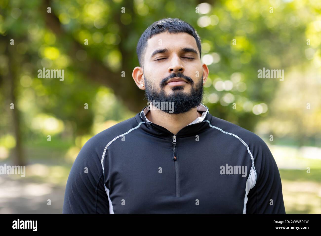 A serene man practicing mindfulness meditation outdoors, eyes closed ...