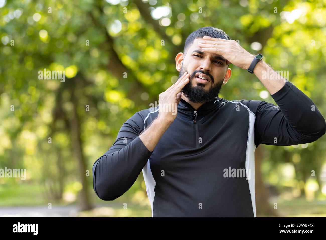 A tired male athlete wipes sweat from his forehead while touching his ...