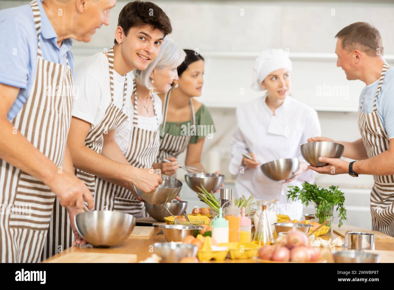 Cooking class - happy friends cooking and talking in kitchen Stock ...