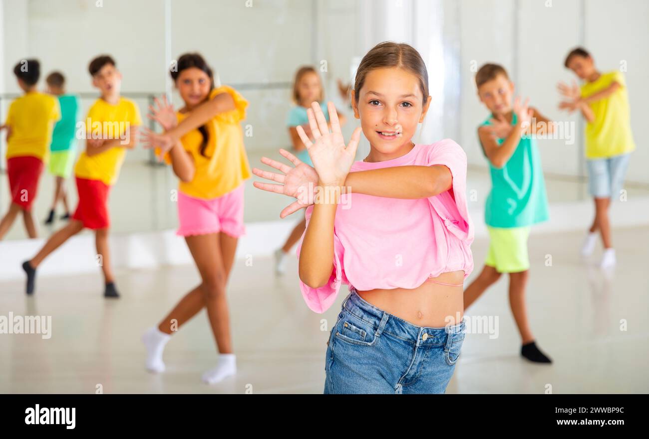 Cheerful preteen girl learning energetic dance in choreography class ...