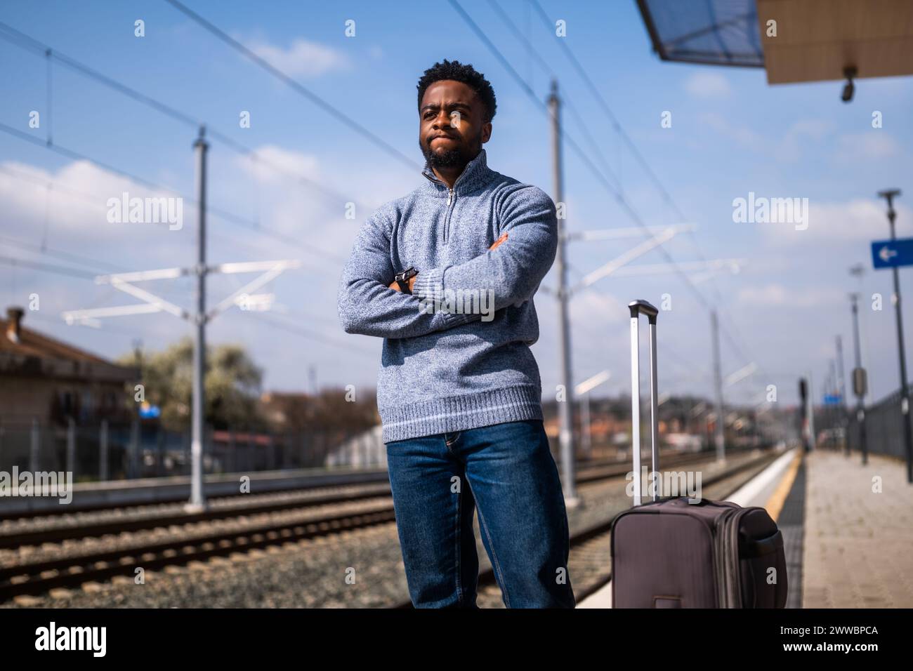 Angry man with a suitcase standing on a railway station Stock Photo - Alamy