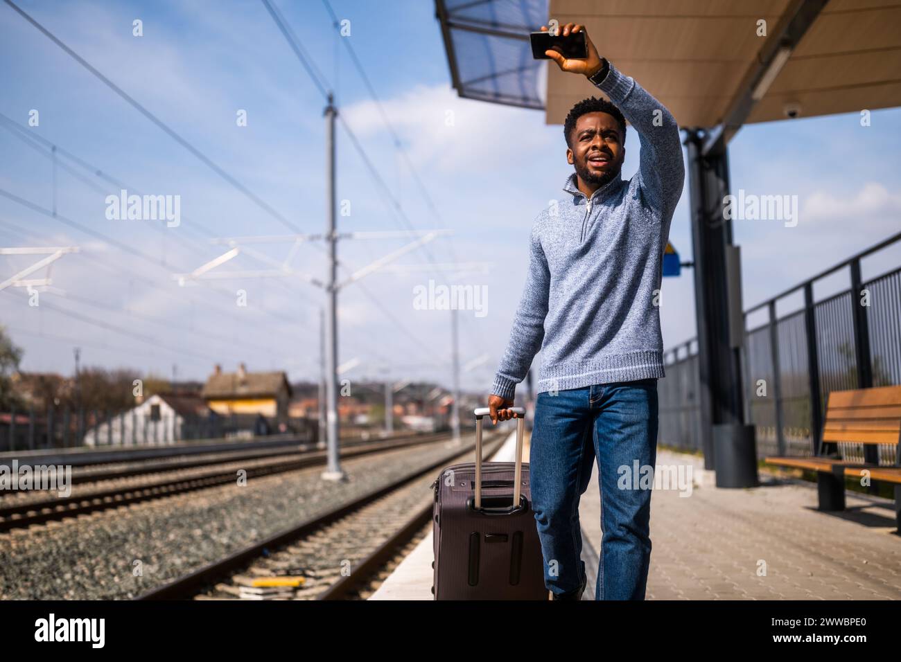 Man waving to a leaving train and running along railway station with ...