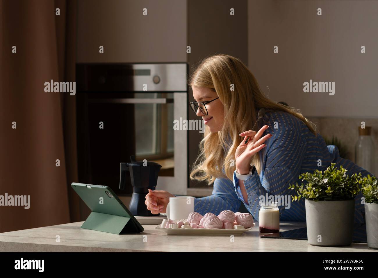 Woman multitasking with tablet and breakfast. Morning routine at remote ...