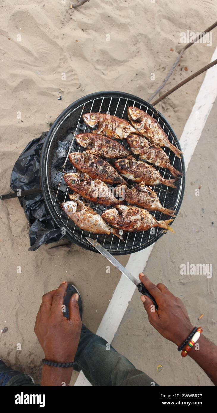 Grilling fish over charcoal on a sandy beach Stock Photo - Alamy