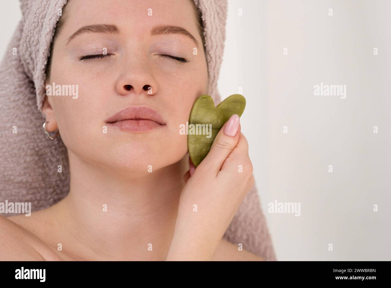 Facial skincare with natural stone. Woman does a facial massage with ...