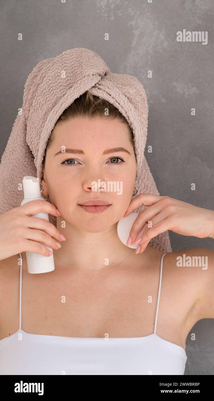 Applying toner after a shower. Young woman cares about facial skin ...
