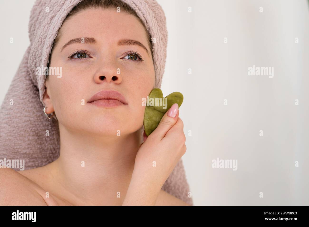 Facial skincare with natural stone. Woman does a facial massage with ...