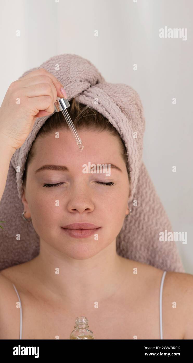 Serum application on forehead. A young woman cares about skin health ...