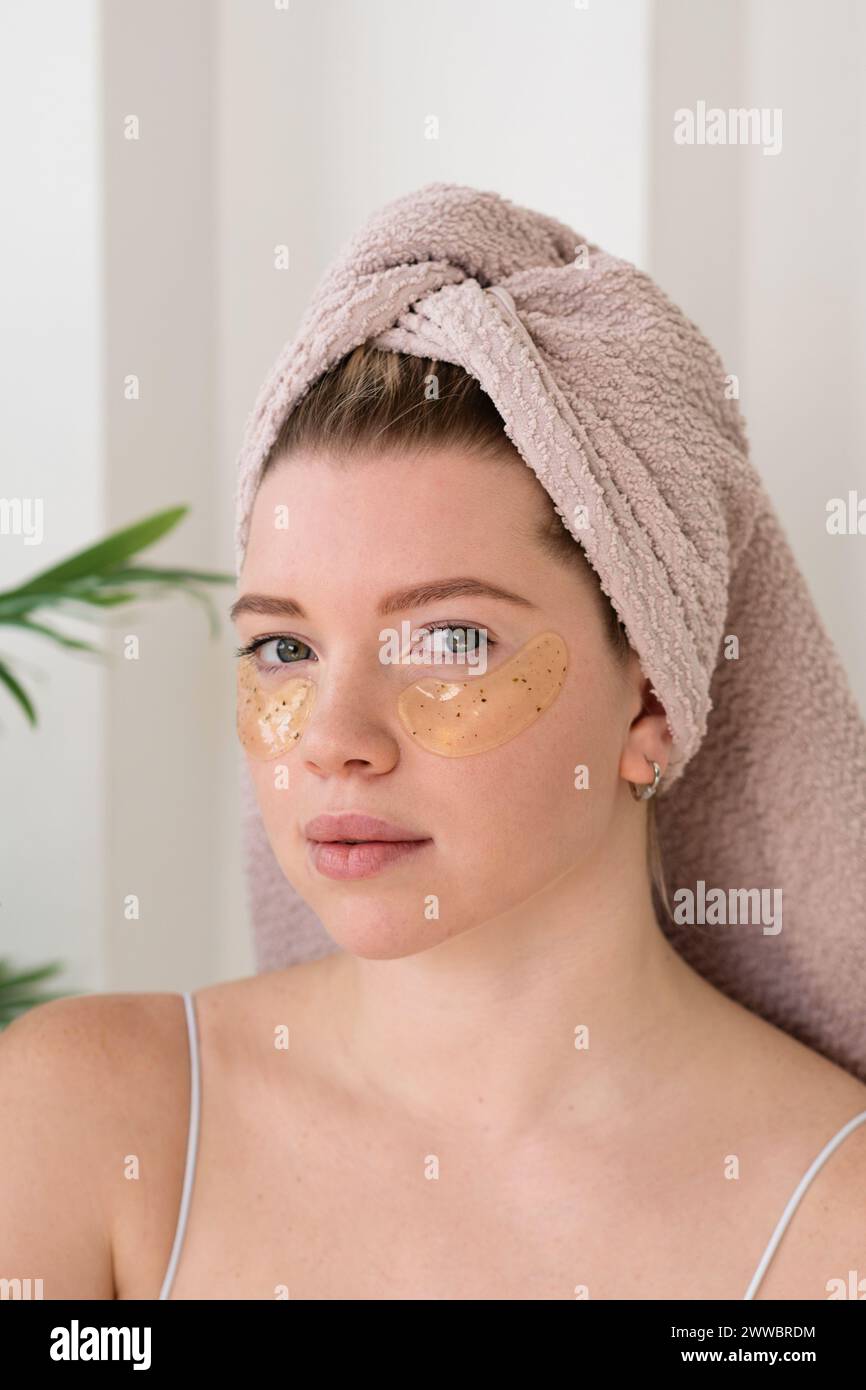 Applying eye patches in skincare routine. Woman with natural face using ...