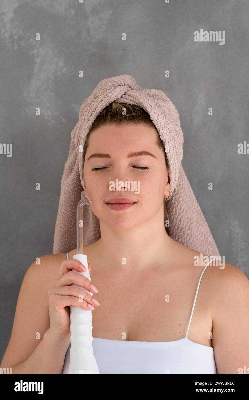 Microcurrent facial massage therapy. Girl using microcurrent provides ...