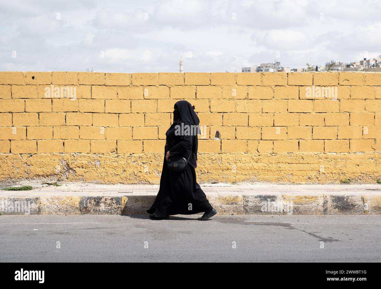 Amann, Jordan. 23rd Mar, 2024. A woman walks along a wall in the ...