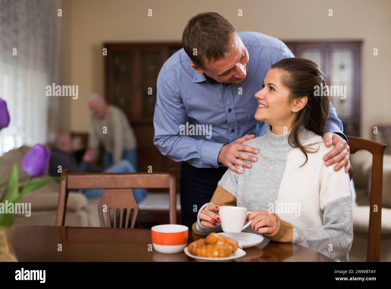 Happy couple hugging near living room table before drinking tea Stock ...