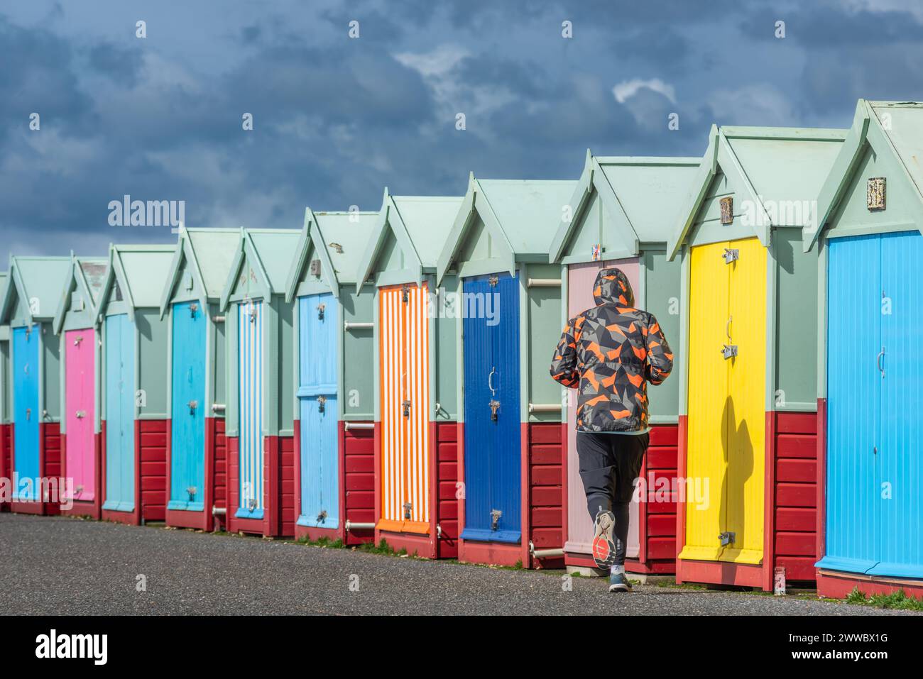 Brighton, March 23rd 2024: A runner passing the colourful beach huts on ...