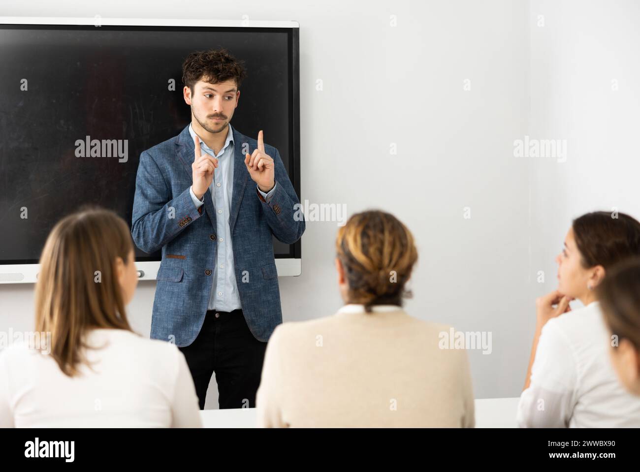 Positive male trainer, conducting advanced training courses to office ...
