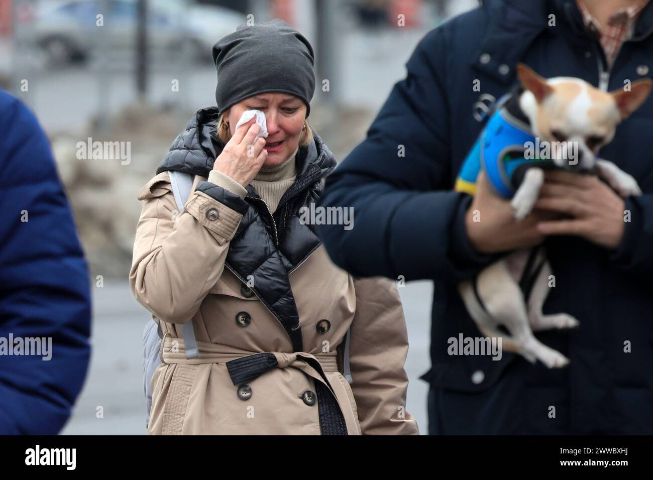 A woman reacts as she comes to place flowers at the fence next to the ...