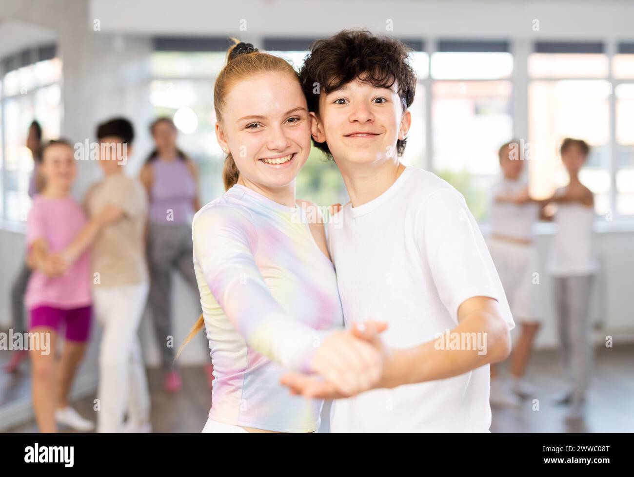 Group of positive teenagers learning to dance tango in dance studio ...