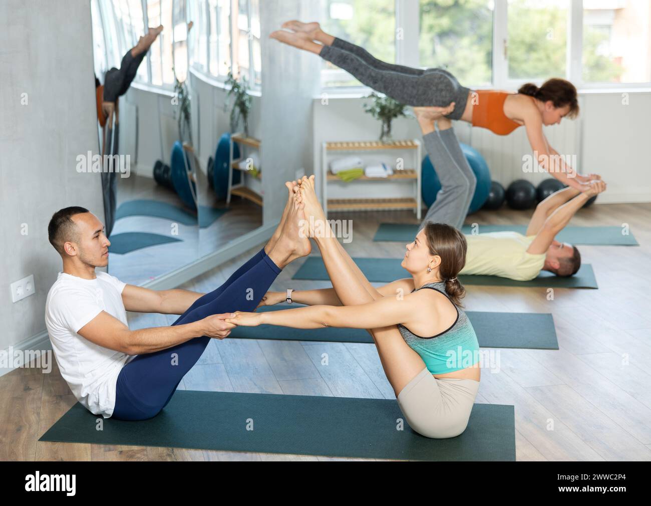 Young girl and man practicing pair yoga training buddy boat pose at gym ...