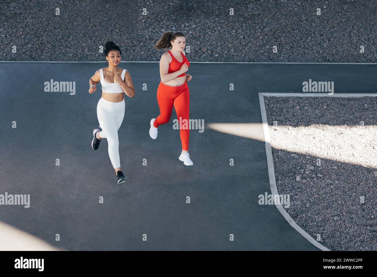 High angle of two females running together. Two women with different ...