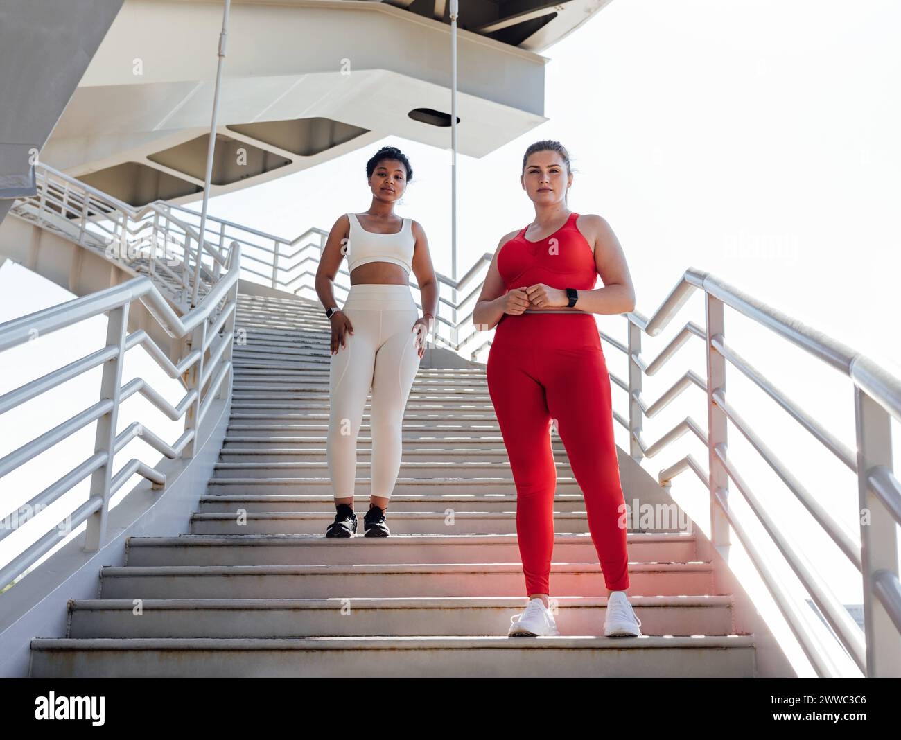 Two females in fitness attire with different colors looking at camera ...