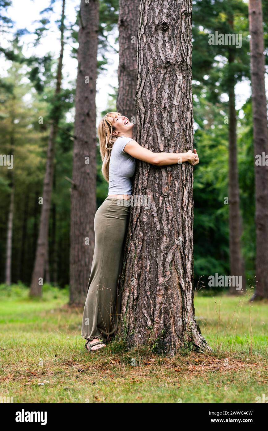 Cheerful young beautiful woman hugging tree in forest Stock Photo - Alamy