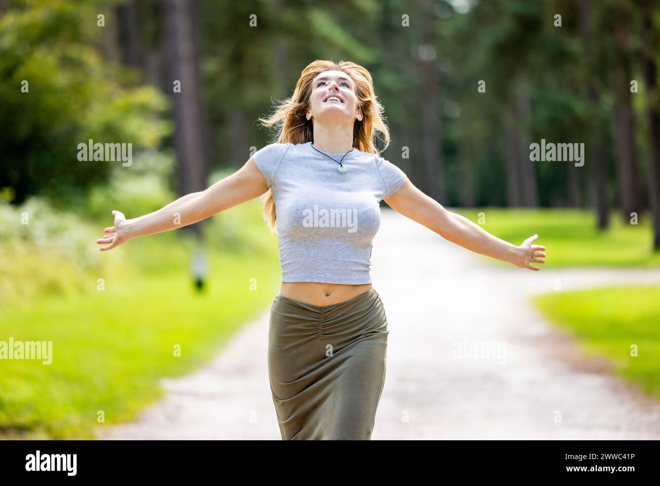 Cheerful woman with arms outstretched walking on road Stock Photo - Alamy