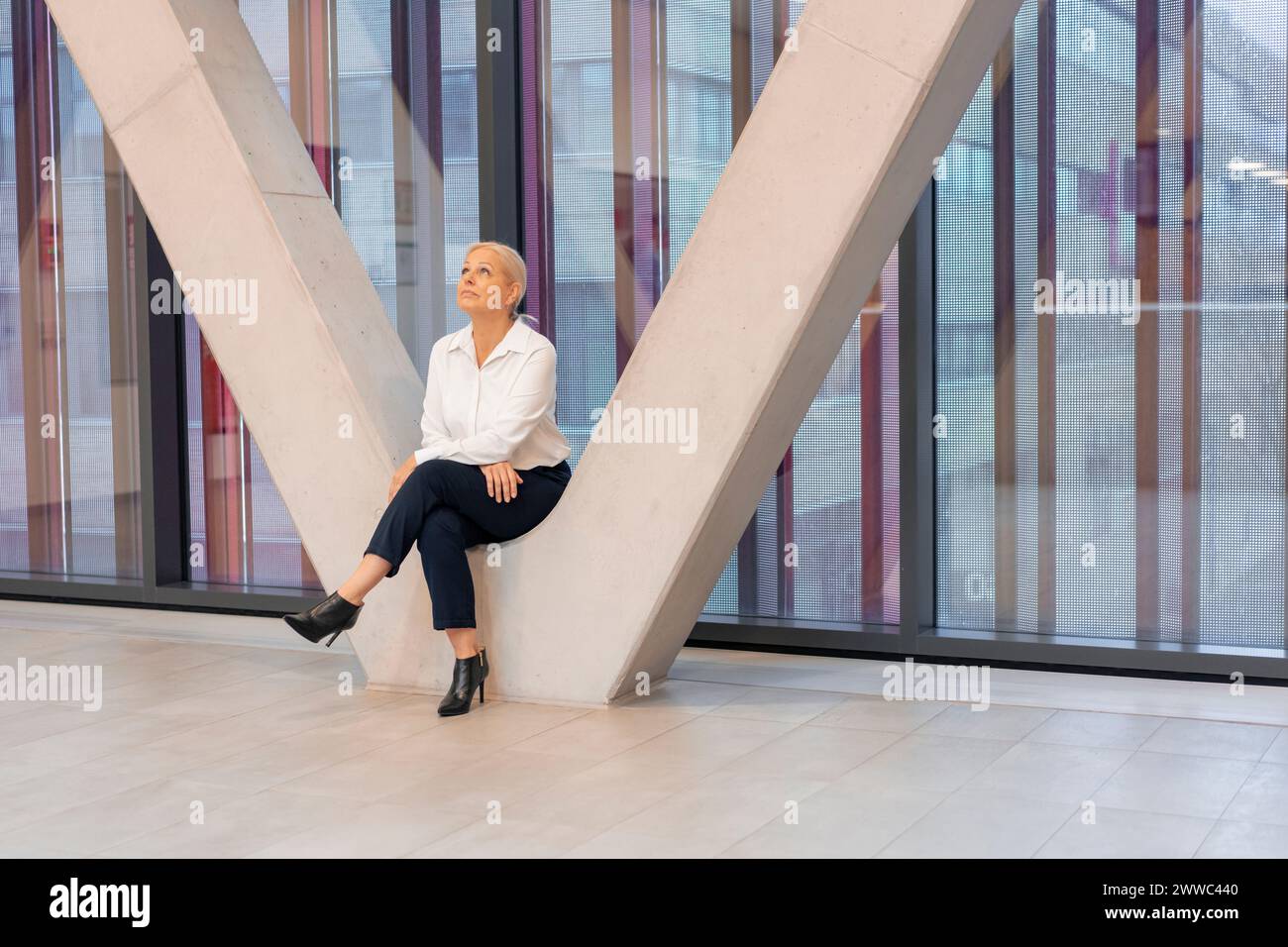 Senior businesswoman sitting amidst architectural column Stock Photo ...