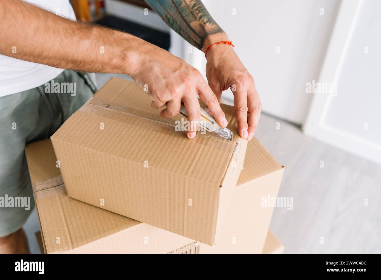 Hands of man opening cardboard box with utility knife at new home Stock ...