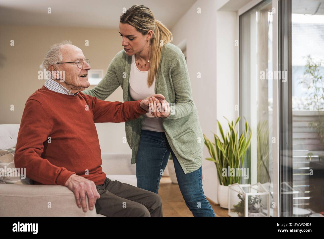 Home caregiver taking care of senior man in living room Stock Photo - Alamy