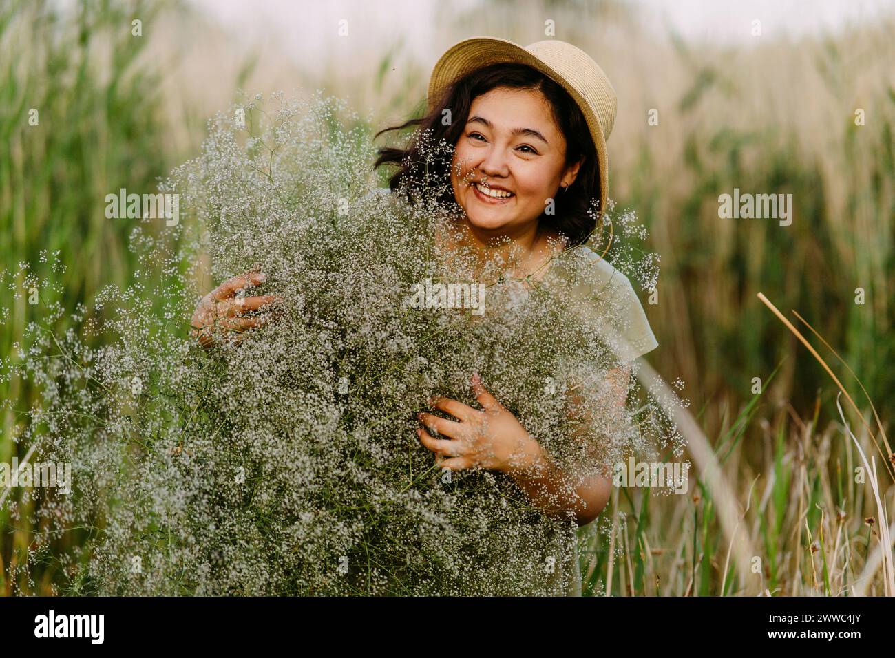 Playful woman with bunch of gypsophila flowers in field Stock Photo - Alamy