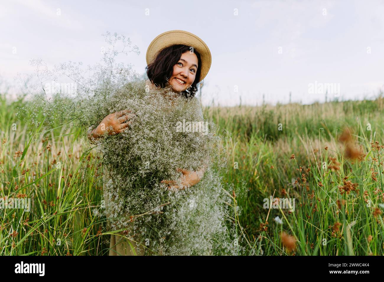 Happy mature woman holding bunch of gypsophila flowers in field Stock ...