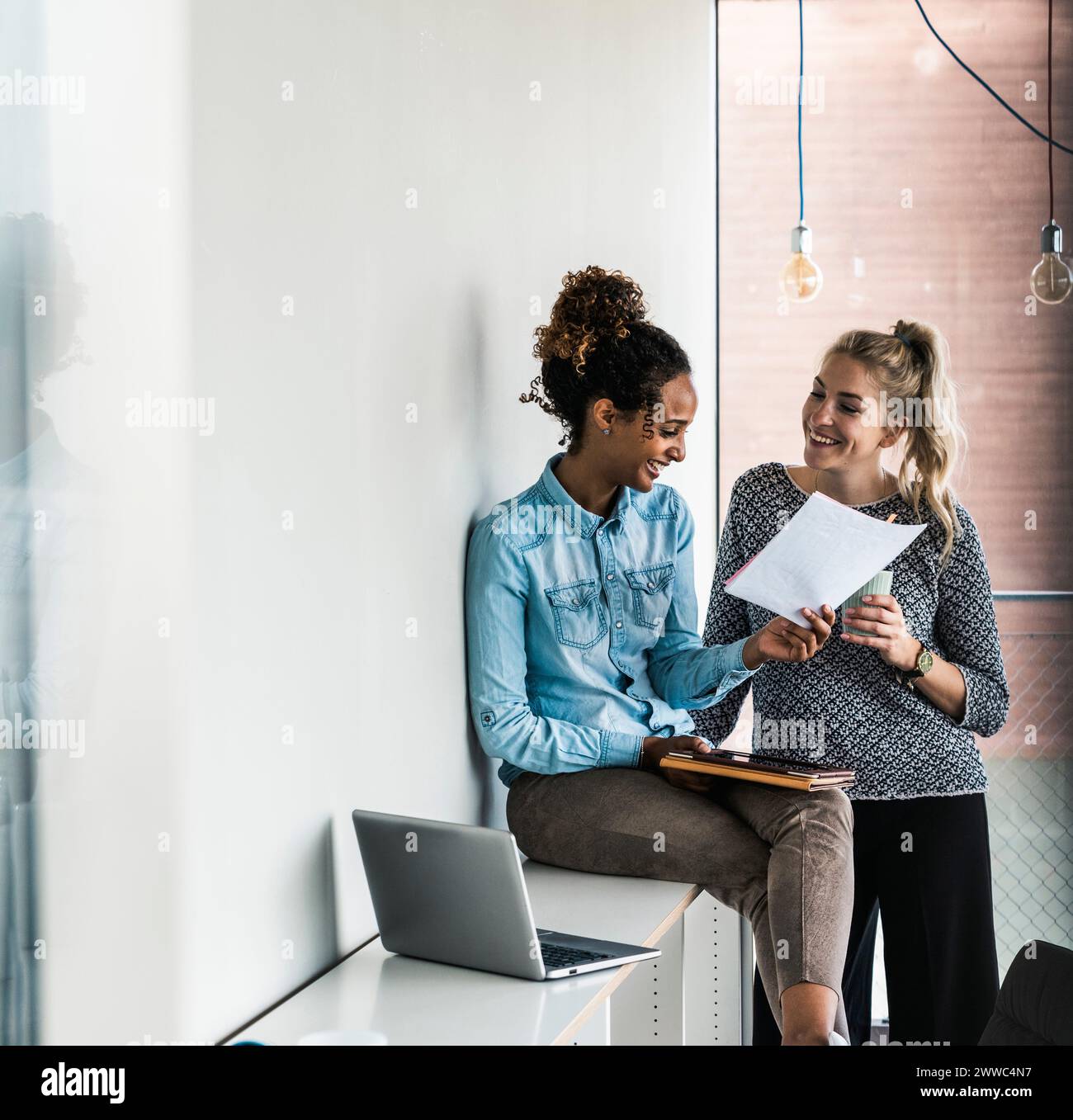 Happy business colleagues having discussion over documents in office ...